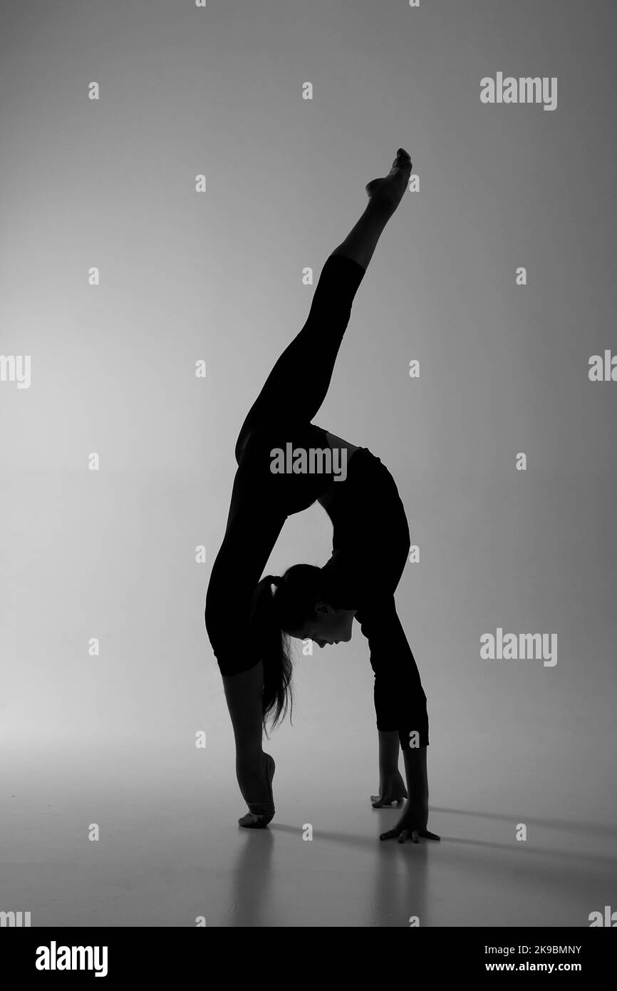 the silhouette of a rhythmic gymnastics girl in a bodysuit shows an ...