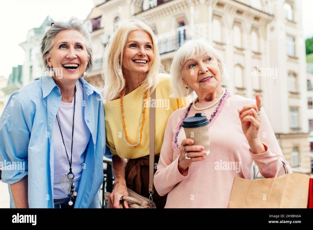 Beautiful happy senior women meeting outdoors and shopping in the city ...