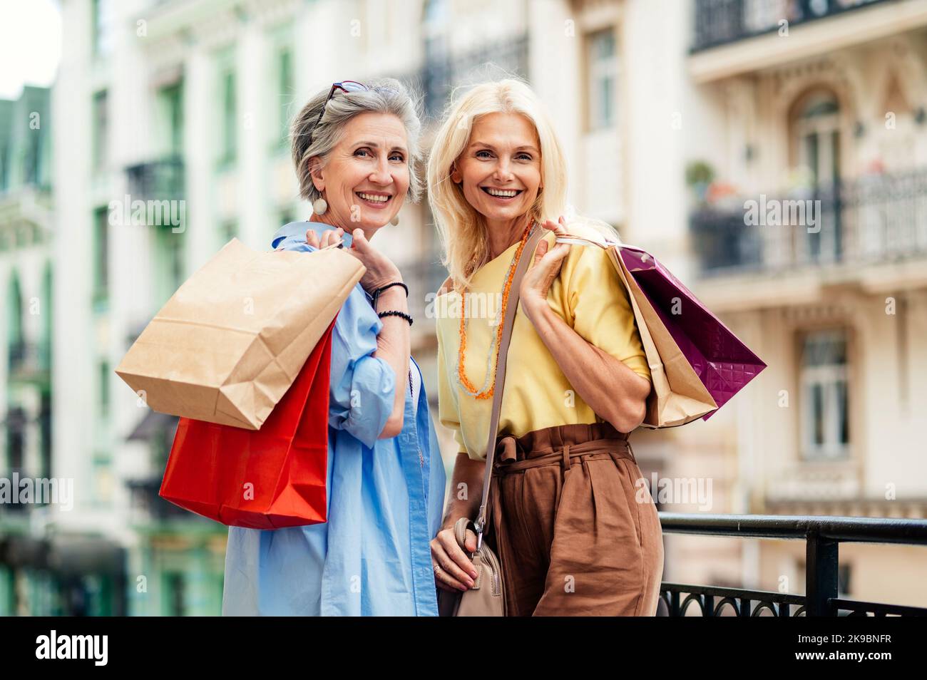 Beautiful happy senior women meeting outdoors and shopping in the city ...