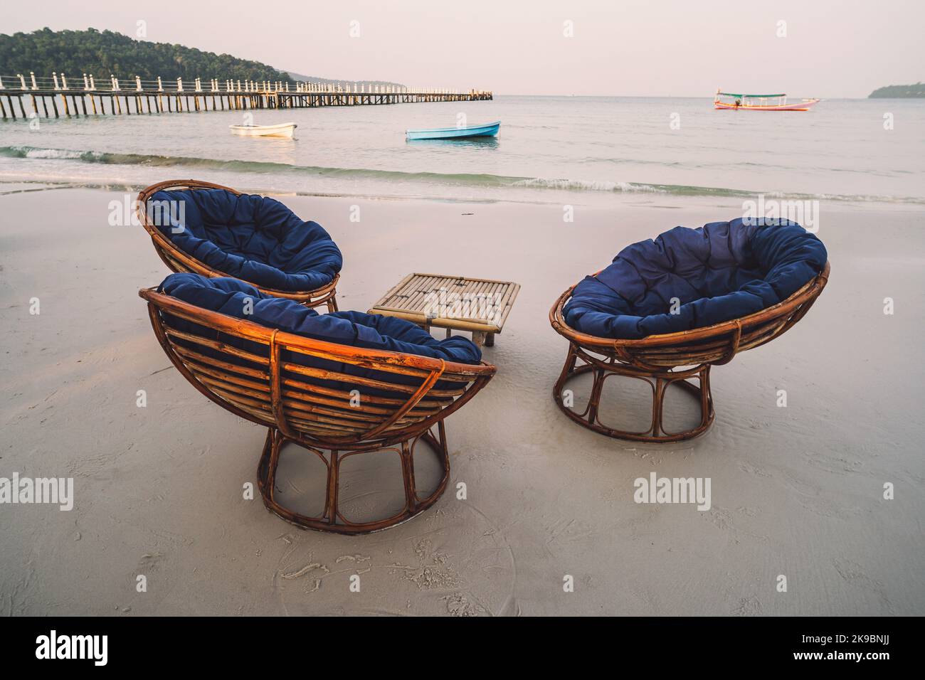 Wooden cafe table and chairs on a tropical beach with blue sea on ...