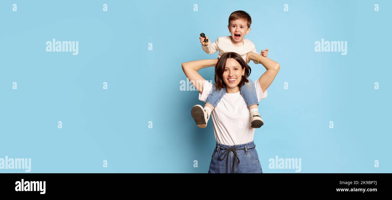 Young happy mother with little kid having fun isolated on blue ...