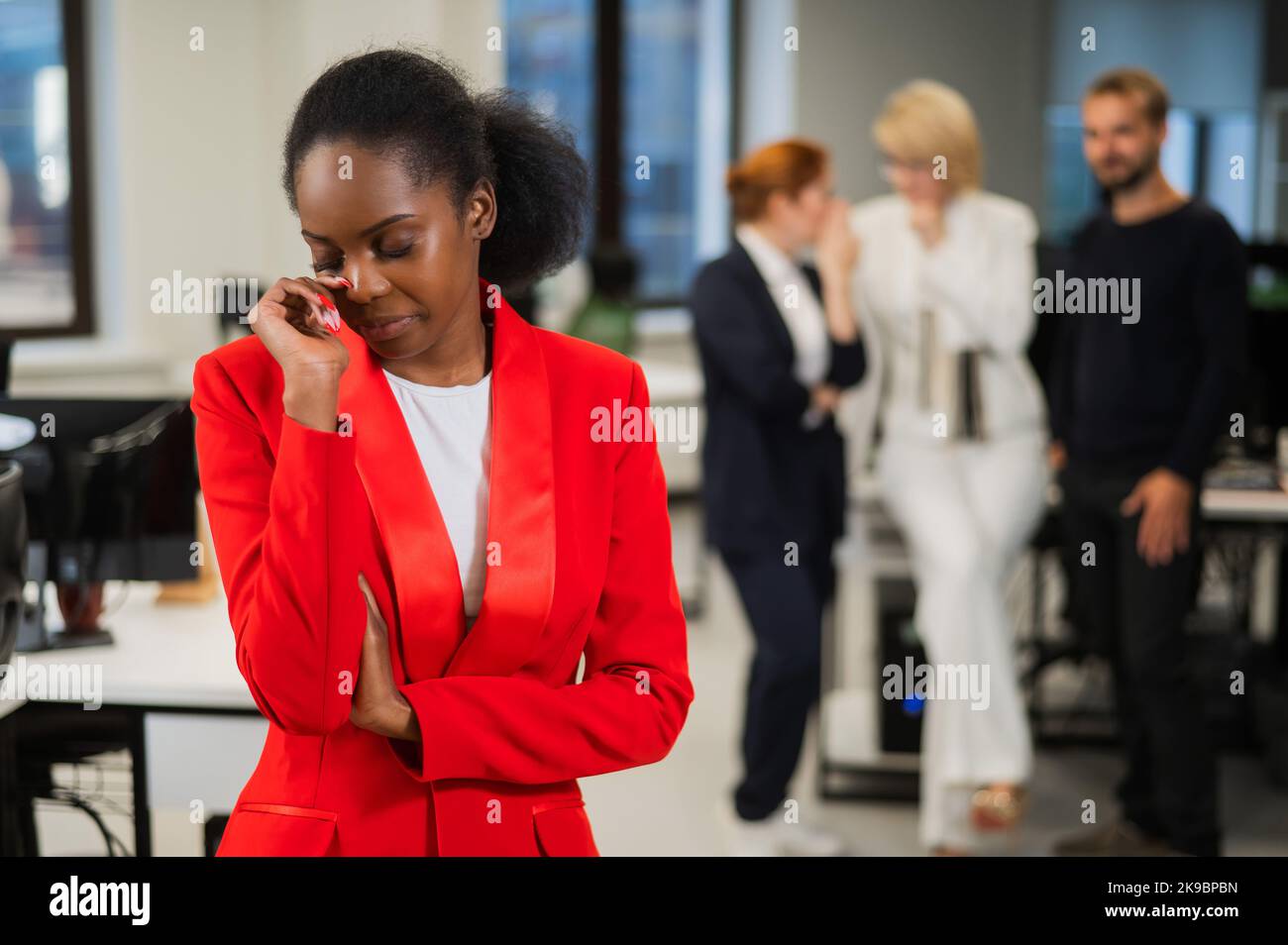 Young african woman crying because of the ridicule of colleagues ...