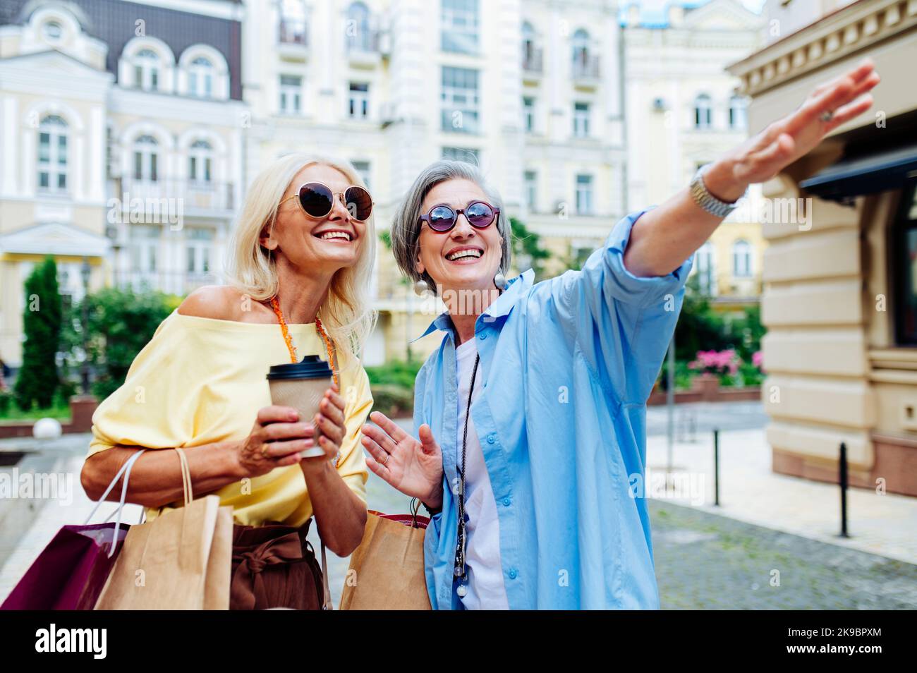 Beautiful happy senior women meeting outdoors and shopping in the city ...