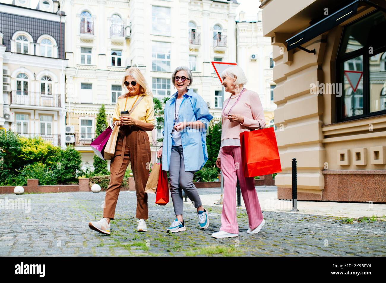 Beautiful happy senior women meeting outdoors and shopping in the city ...