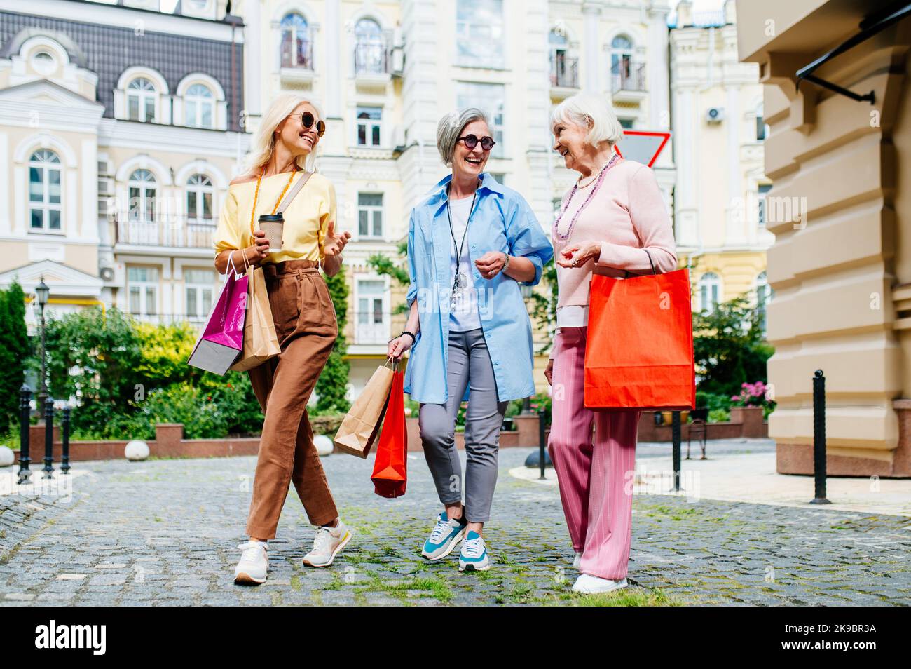 Beautiful happy senior women meeting outdoors and shopping in the city ...