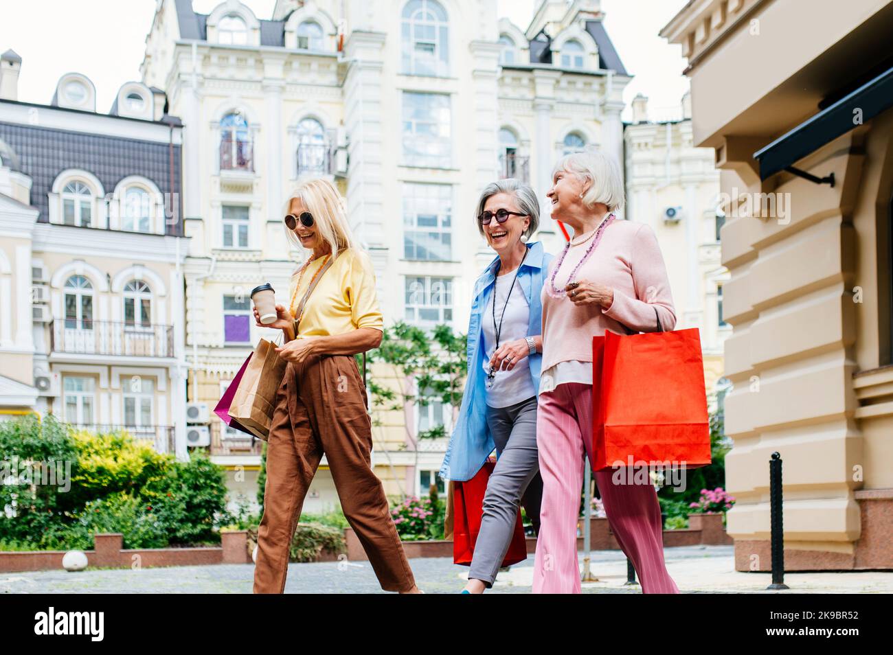 Beautiful happy senior women meeting outdoors and shopping in the city ...