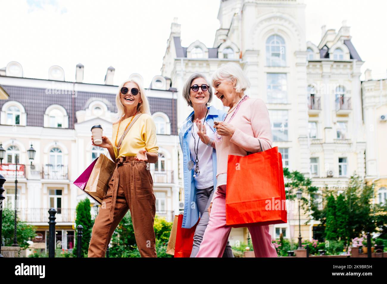 Beautiful happy senior women meeting outdoors and shopping in the city ...