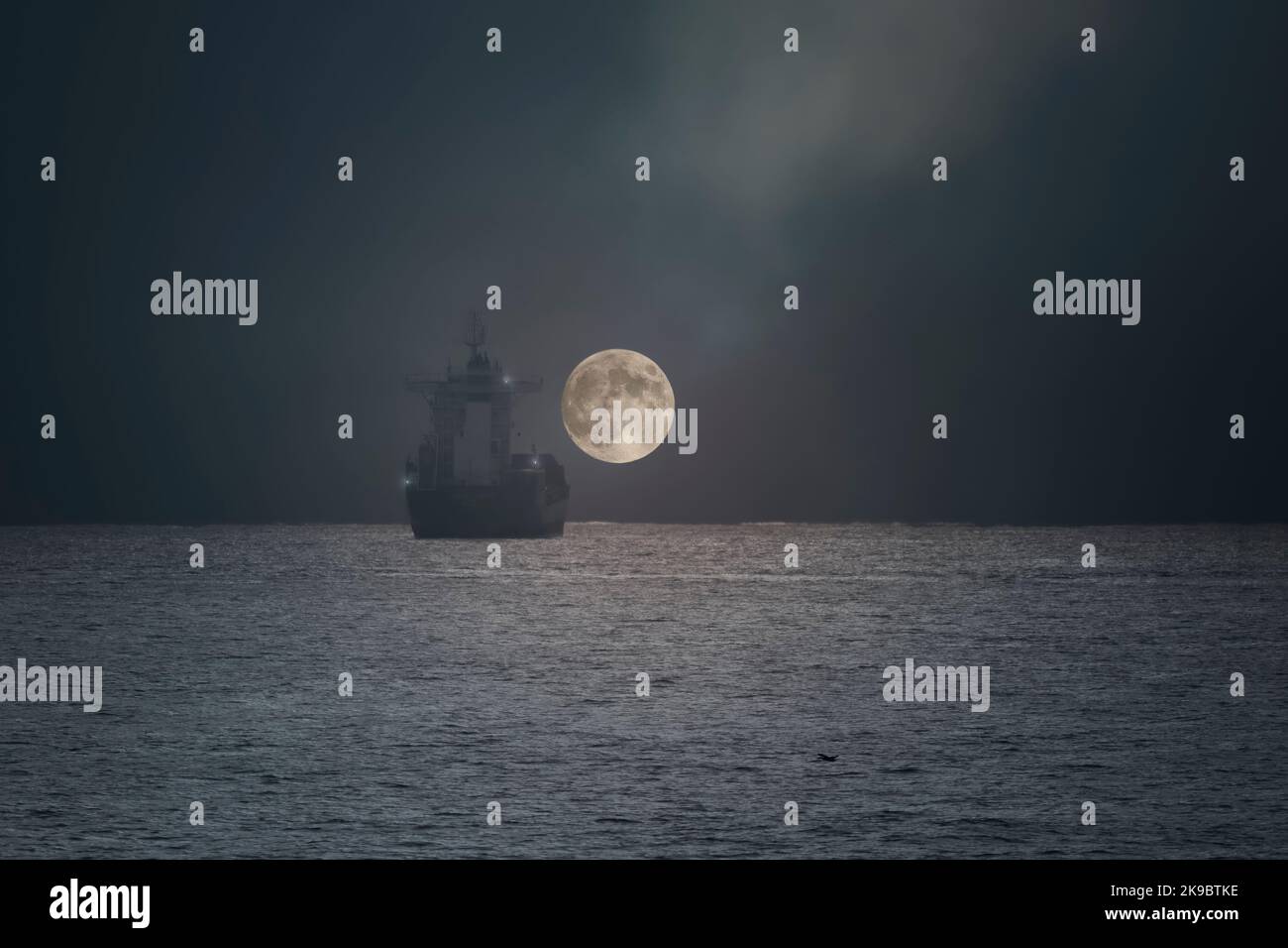Commercial ship on the horizon in a full moon night Stock Photo - Alamy