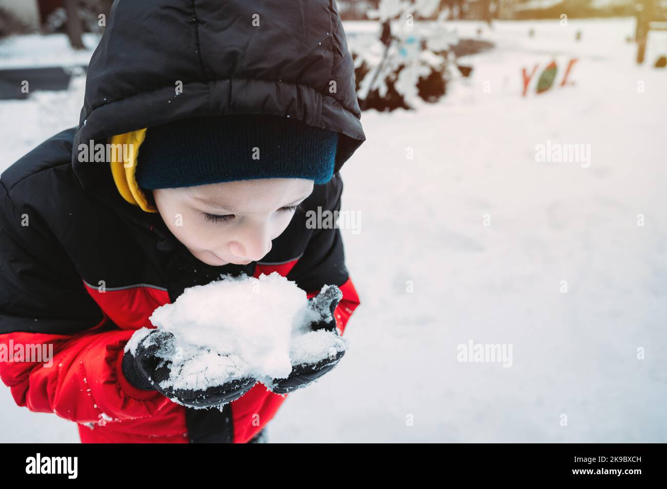 Boy eating and plying with snow and has fun. Outdoor activities for ...