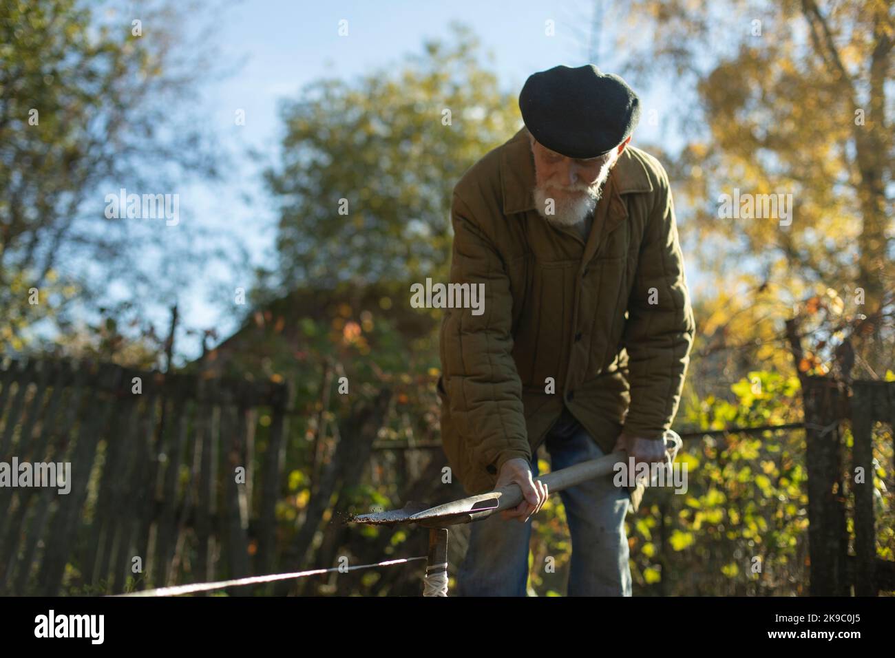 Russian old man in garden. Grandpa works on land. Pensioner works. Man ...