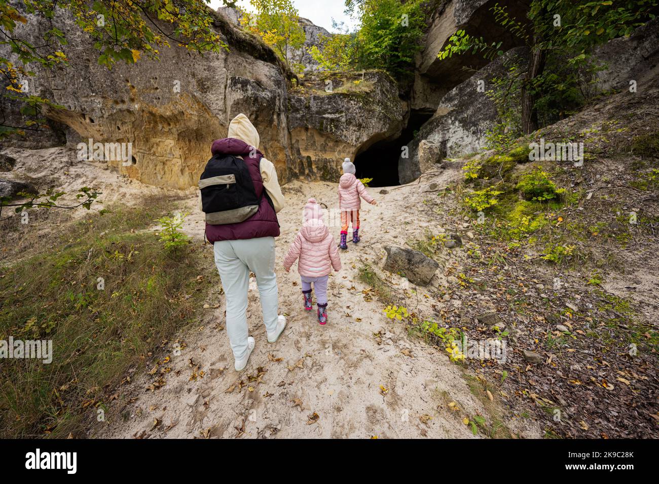 Mother with two daughters explore limestone stone cave at mountain in ...