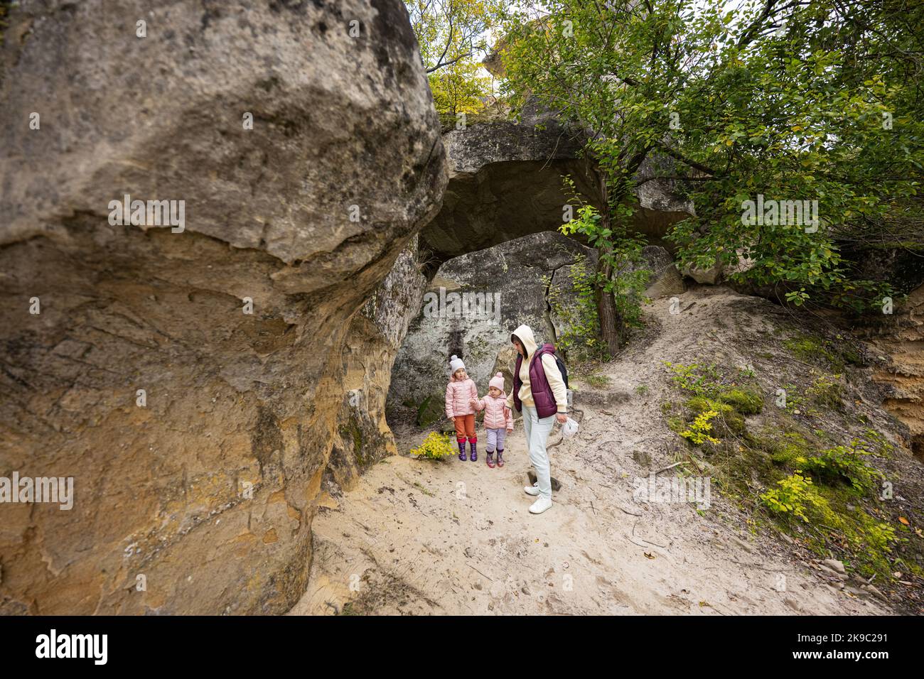 Mother with two daughters explore limestone stone cave at mountain in ...