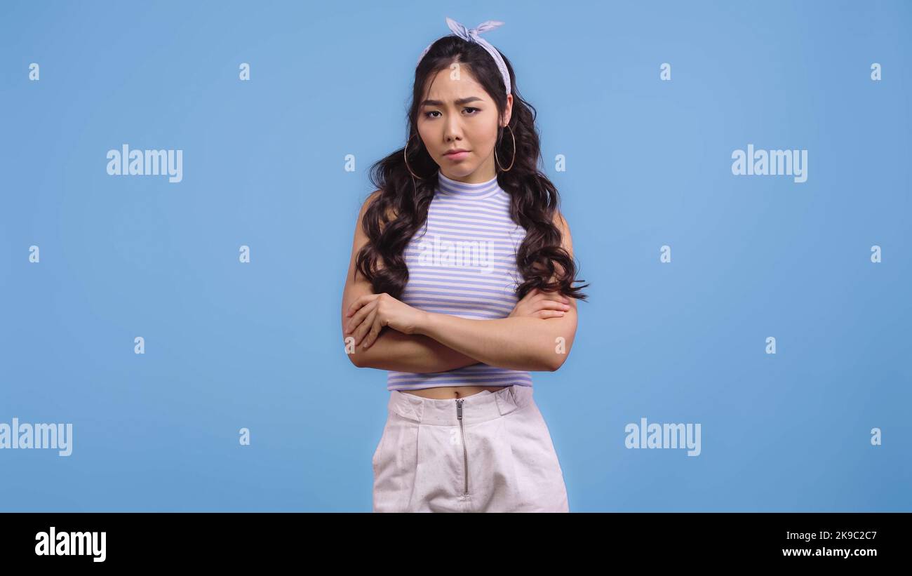 sad asian woman in headband with bow standing with crossed arms ...