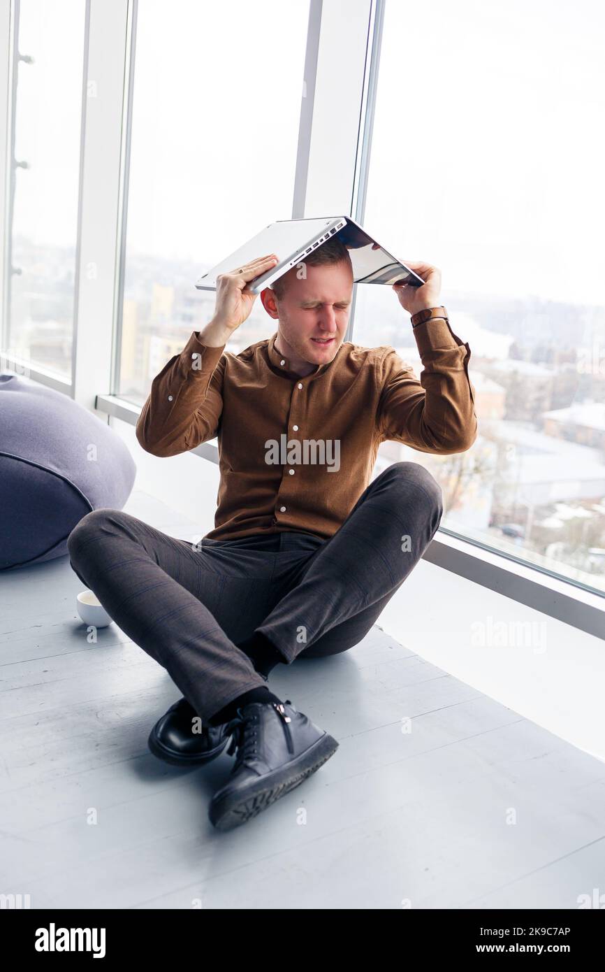 Handsome young male manager is sitting on the floor with the phone near ...