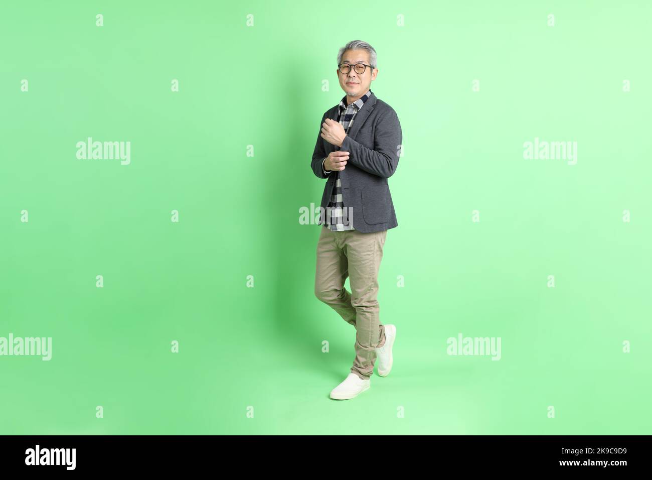 The 40s adult Asian man stnading on the green background with smart ...