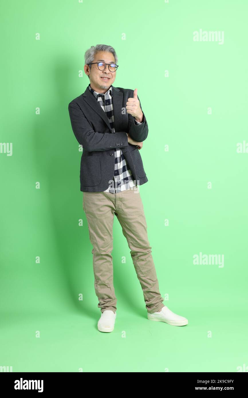 The 40s adult Asian man stnading on the green background with smart ...