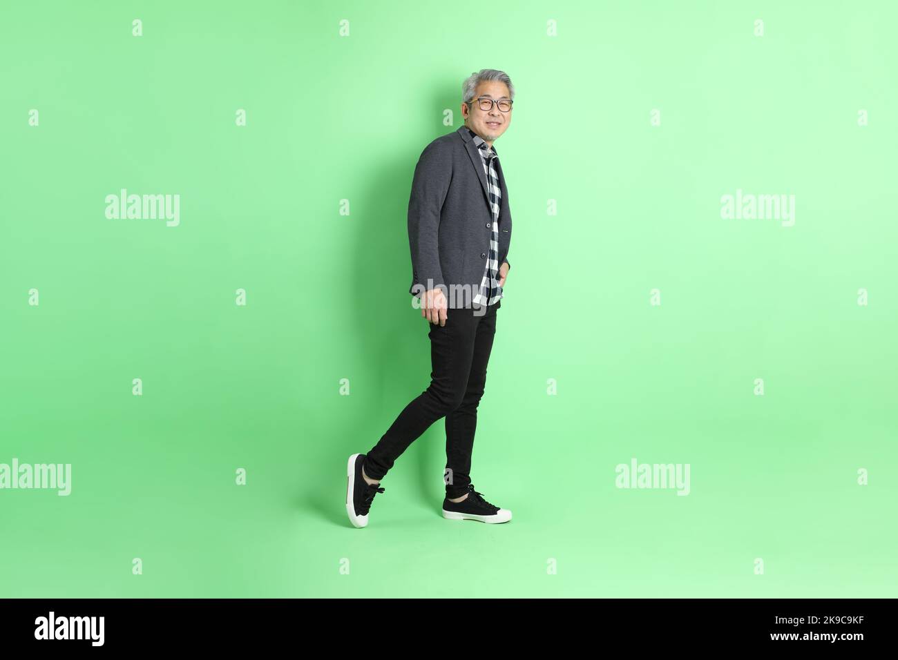 The 40s adult Asian man stnading on the green background with smart ...