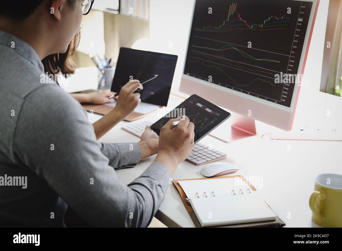 An investment expert points a pen at a computer monitor to analyze the ...