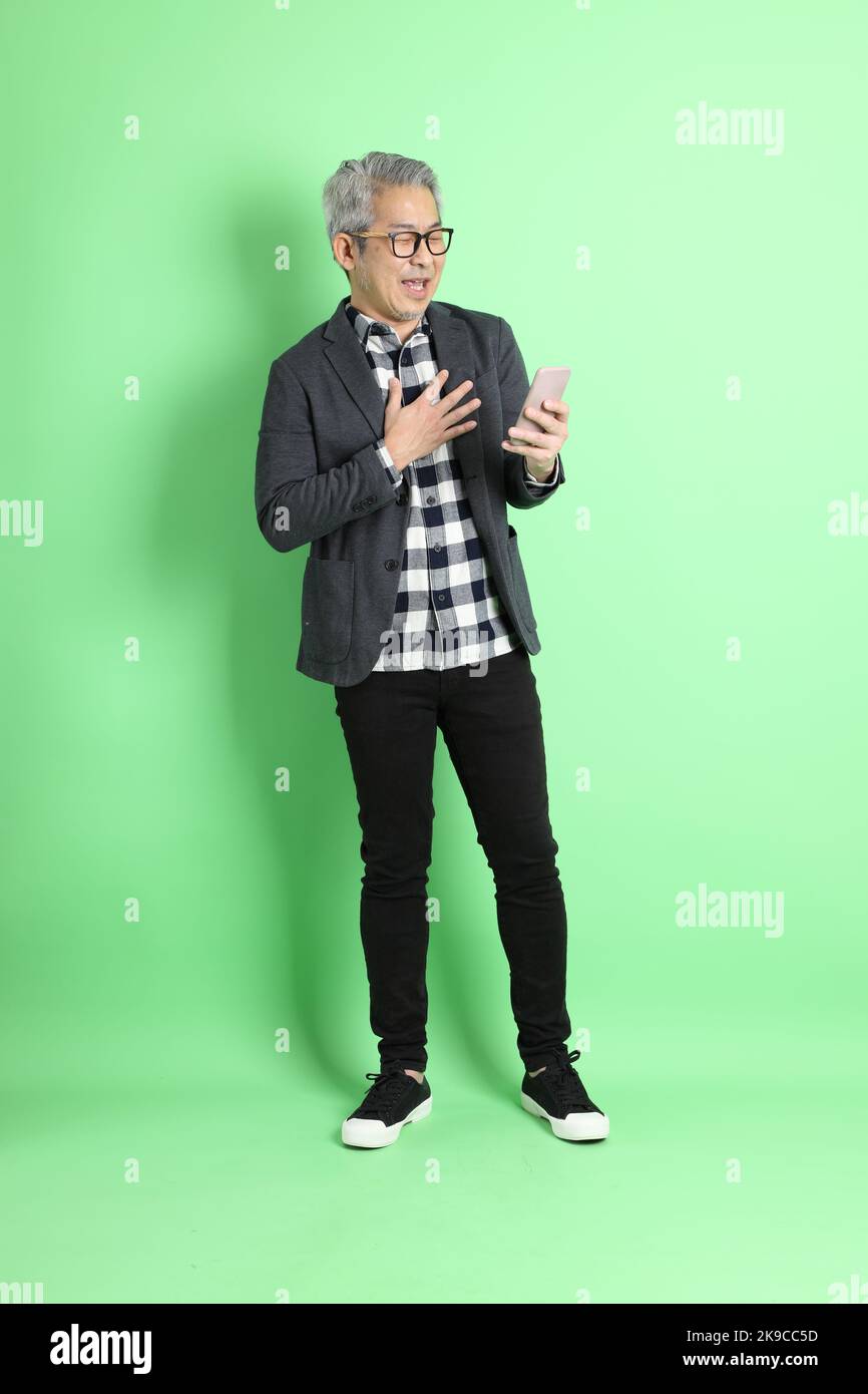 The 40s adult Asian man stnading on the green background with smart ...