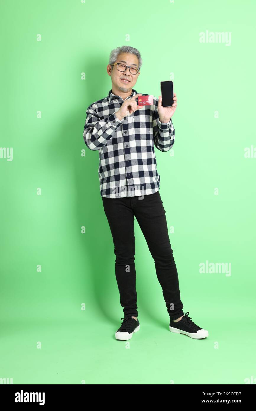 The 40s adult Asian man stnading on the green background with smart ...