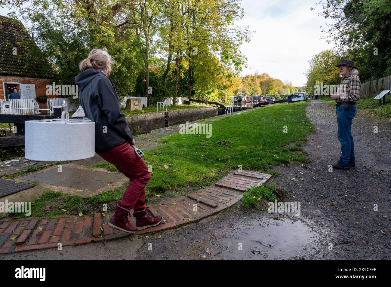 An older woman pushing open the lock gates at Caen Hill Locks on the ...