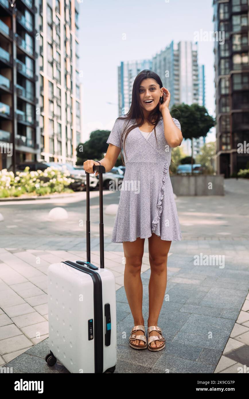 Stylish woman with suitcase looking at camera Stock Photo - Alamy