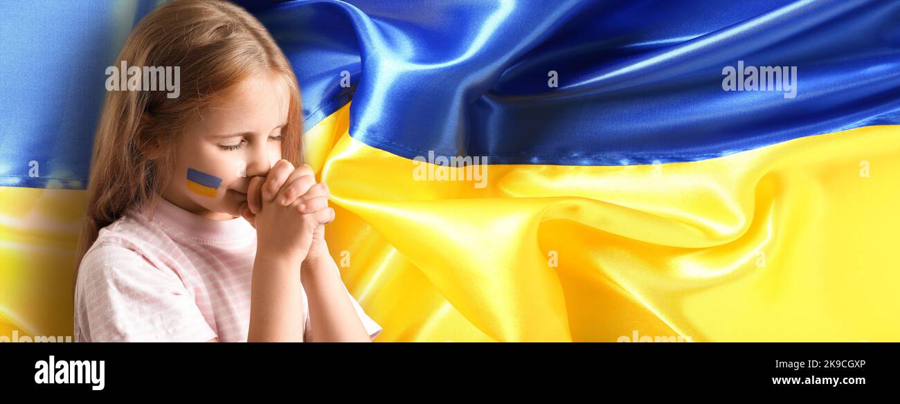 Praying little girl against flag of Ukraine Stock Photo - Alamy