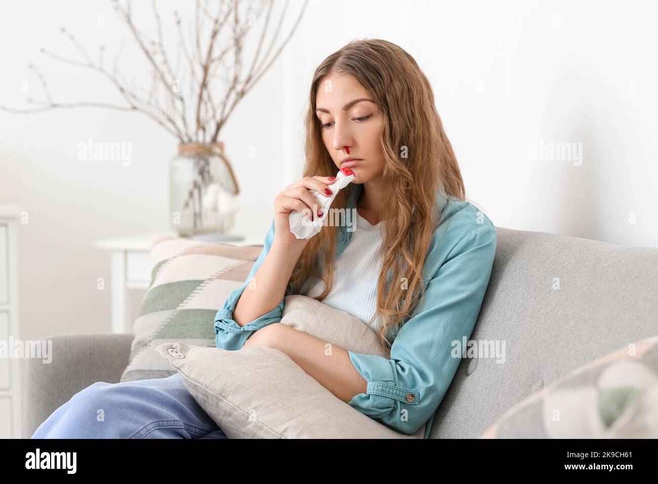 Young woman with nosebleed and tissue at home Stock Photo - Alamy