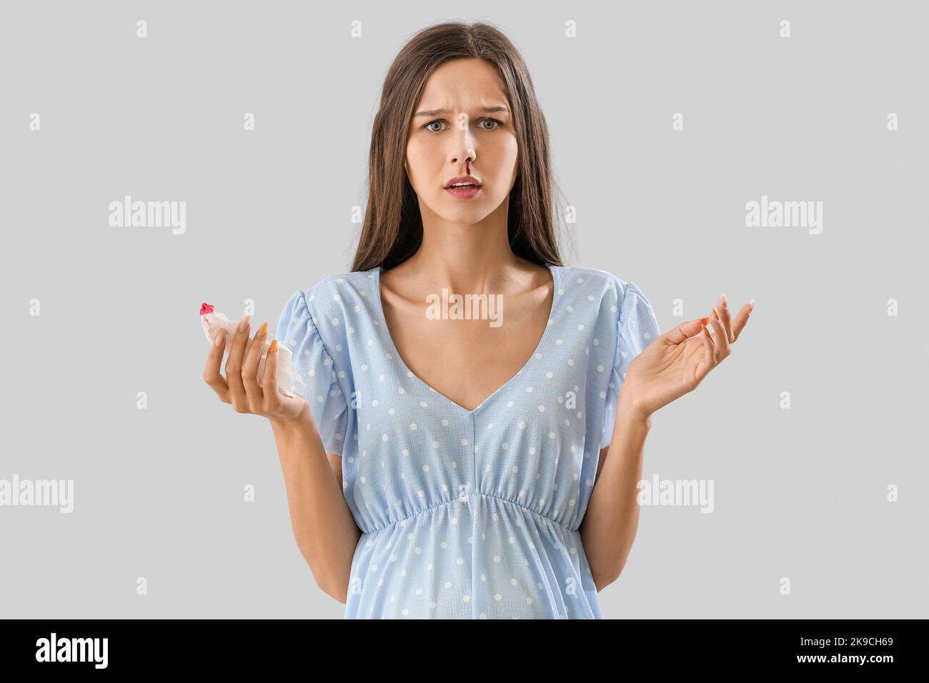 Young pregnant woman with nosebleed and tissue on light background ...