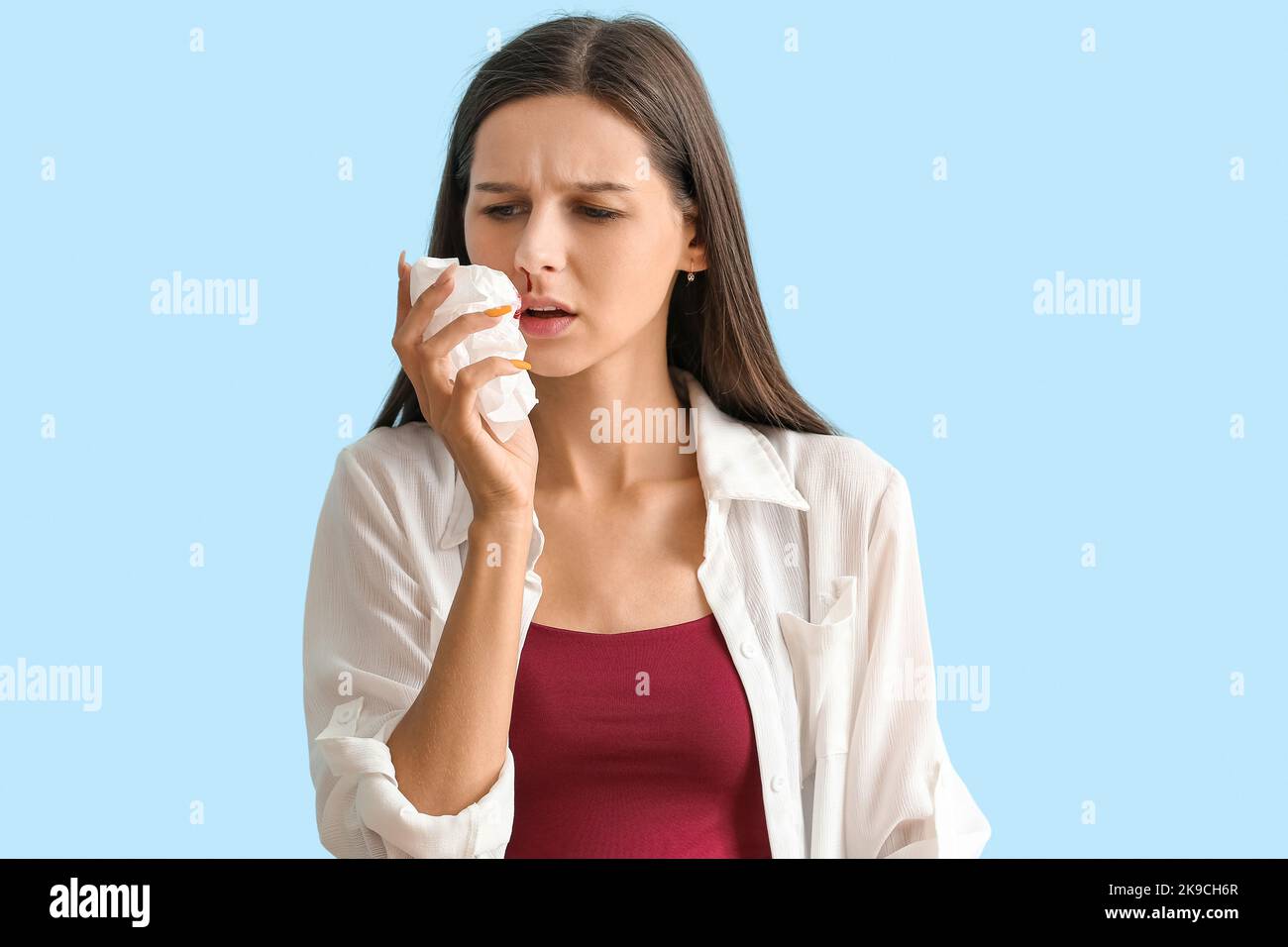 Young woman with nosebleed and tissue on blue background, closeup Stock ...