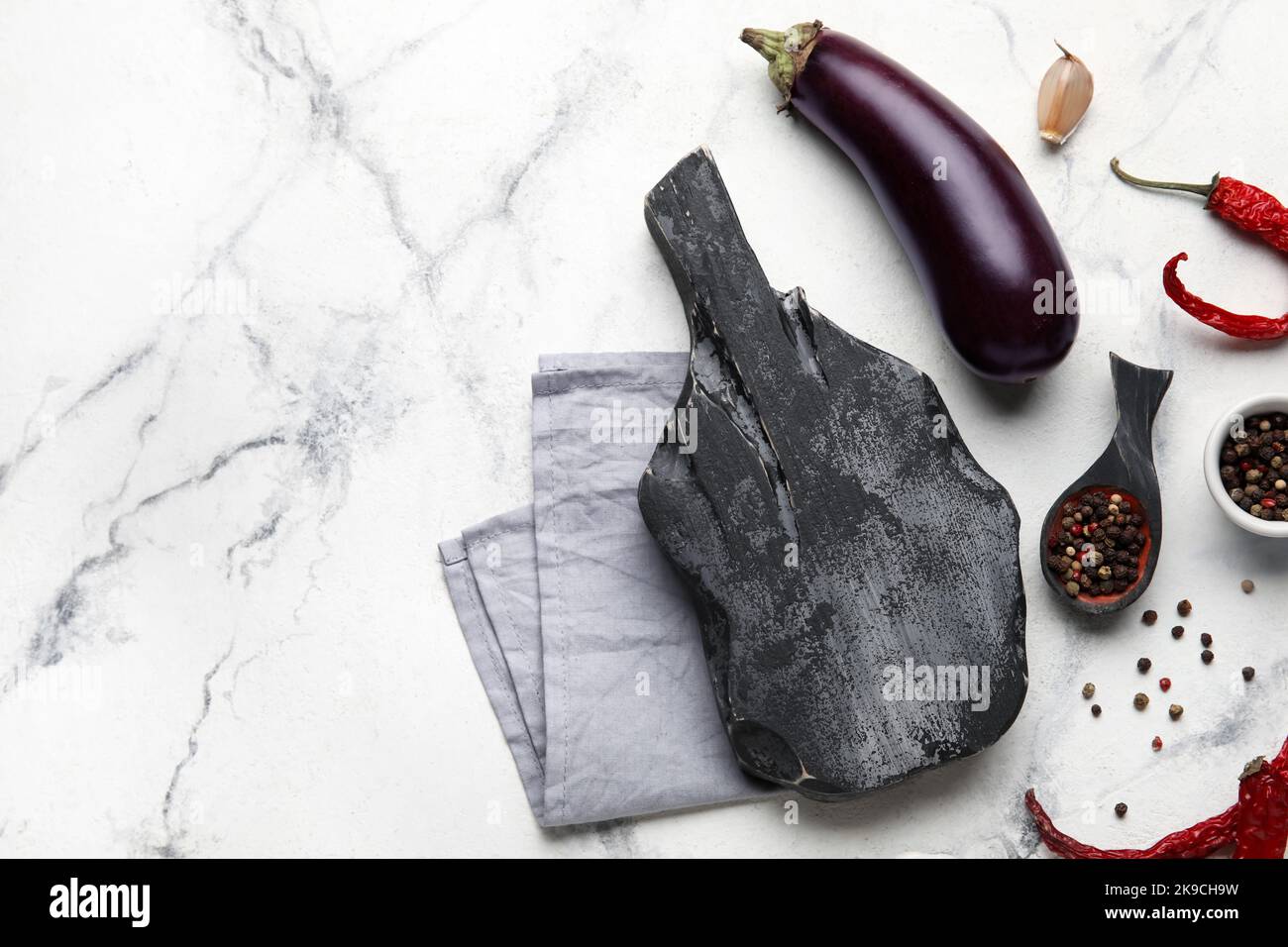 Black wooden cutting board, napkin, spoon with spices and eggplant on ...