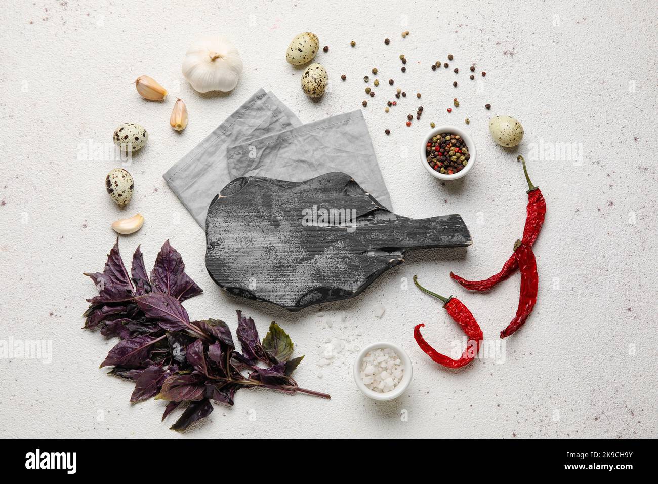 Black cutting board with napkin, spices and vegetables on white ...