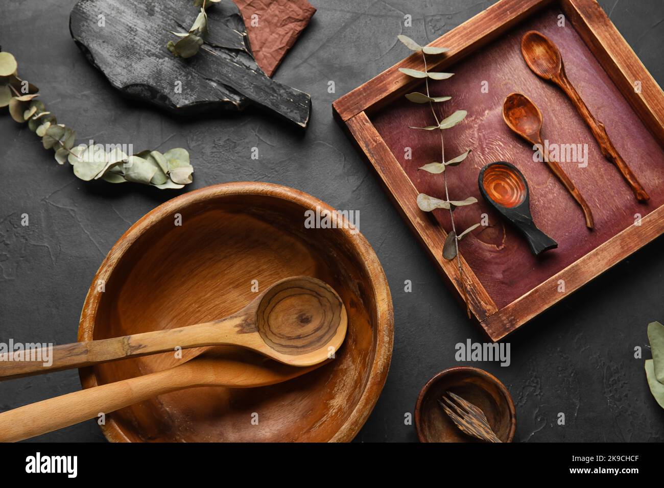 Wooden cooking utensils and eucalyptus branches on dark background ...