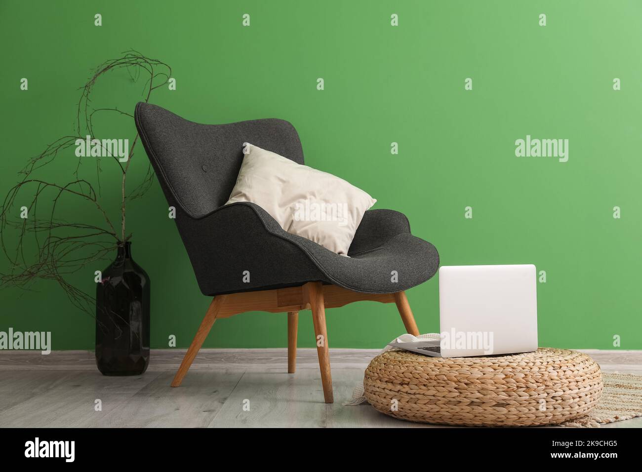 Stylish armchair with pillow and modern laptop near color wall Stock ...