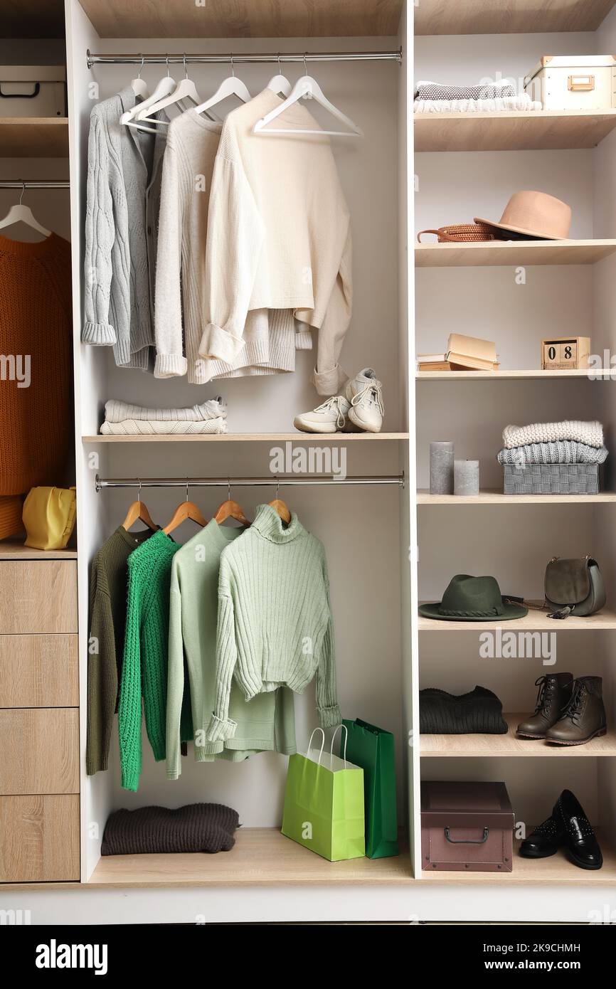 Hanging sweaters and shelves with accessories in wardrobe Stock Photo ...