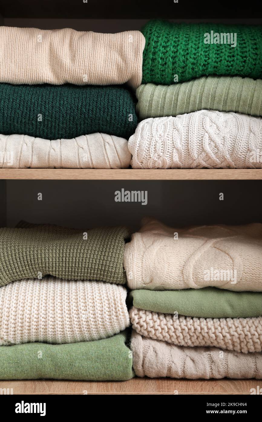 Folded sweaters on shelves in wardrobe, closeup Stock Photo - Alamy