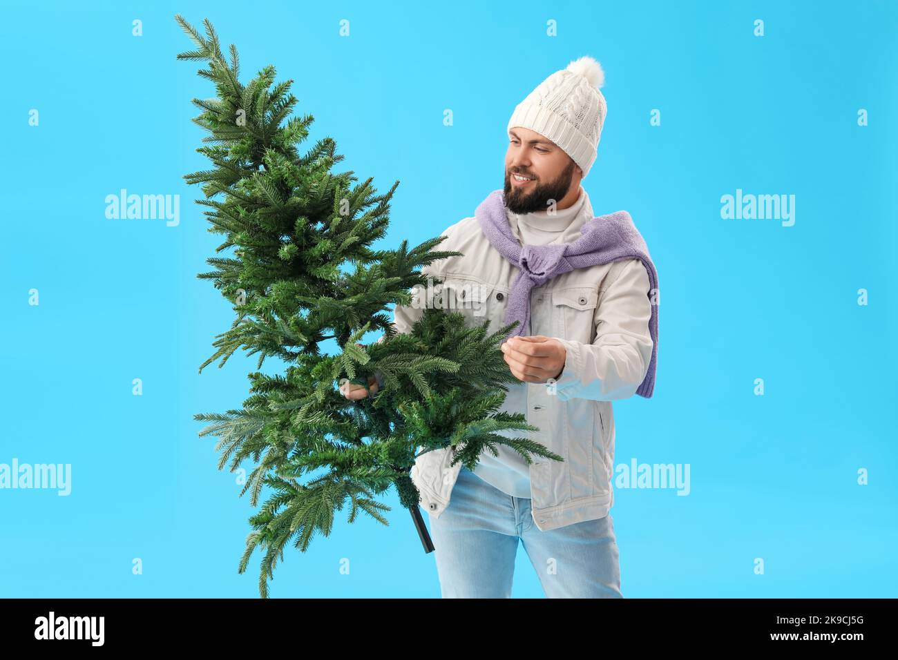 Handsome man with Christmas tree on blue background Stock Photo - Alamy