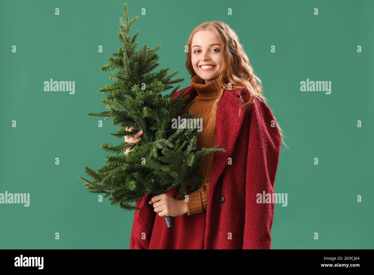 Young woman with Christmas tree on green background Stock Photo - Alamy