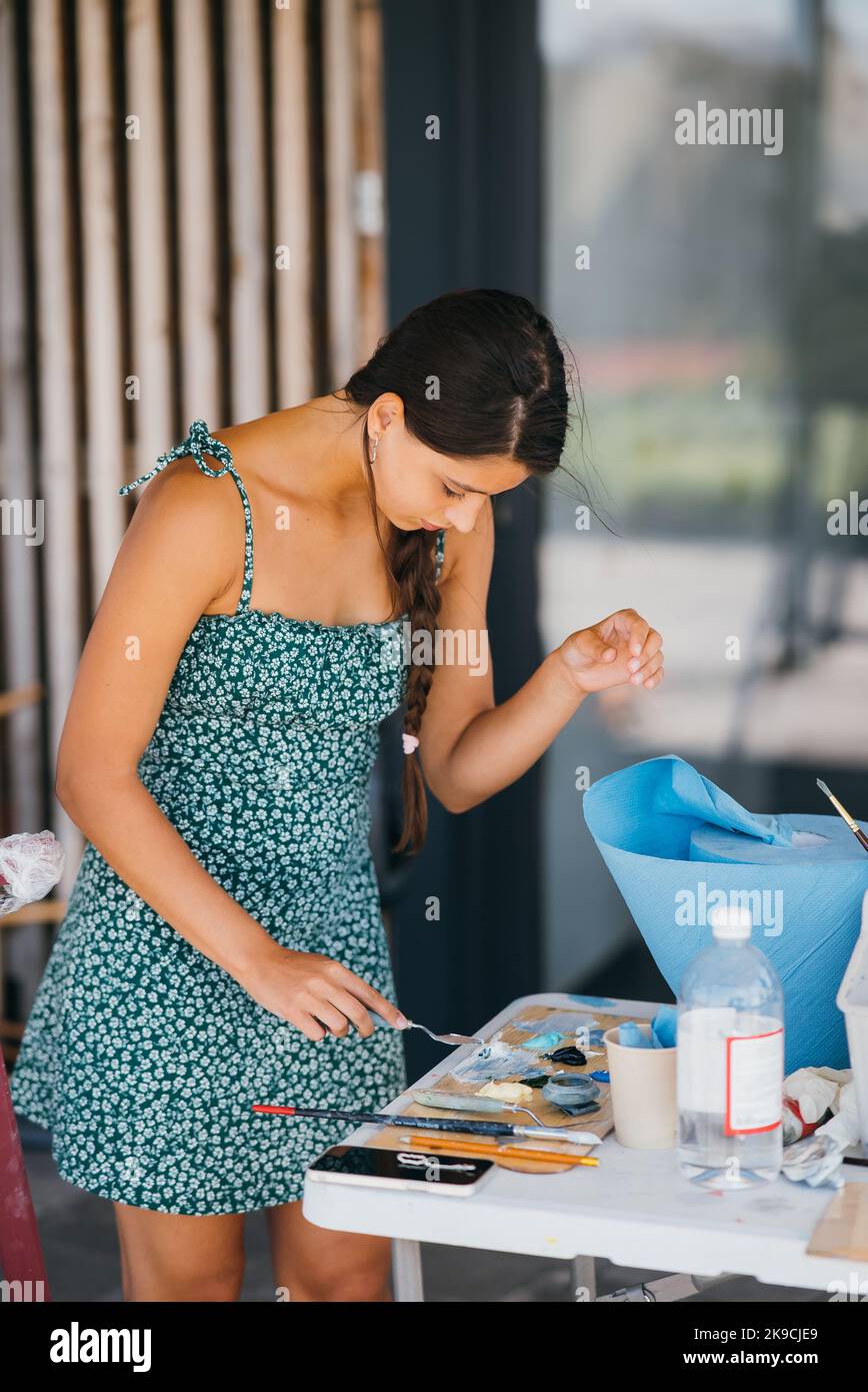 Young beautiful woman artist stands close table with a palette with ...