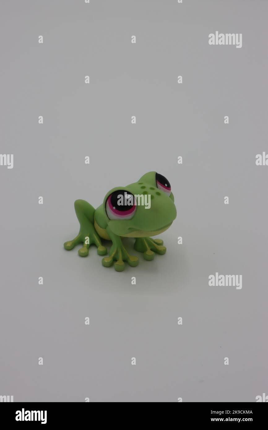 Tiny, cute plastic frog animal figure on a white background ...