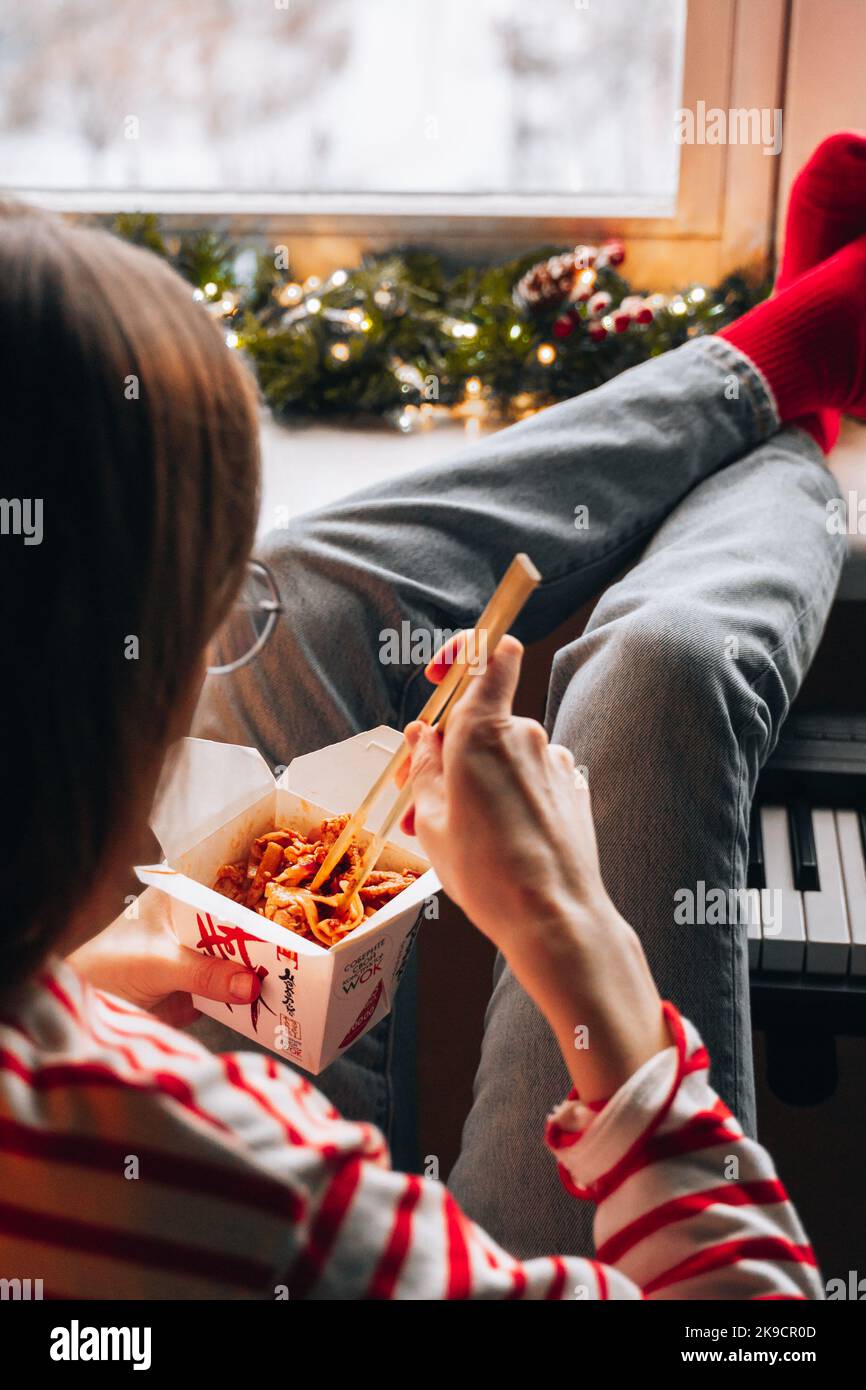 Woman eating fast food from takeaway box asian chinese noodles with ...