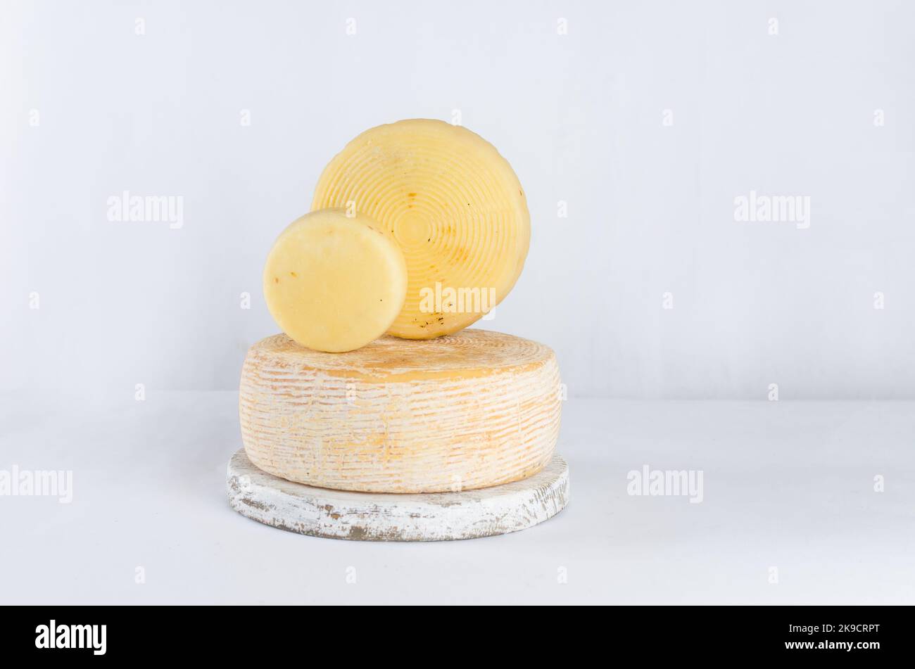 A pile of different kinds cheese heads stacked in vertical row on table ...