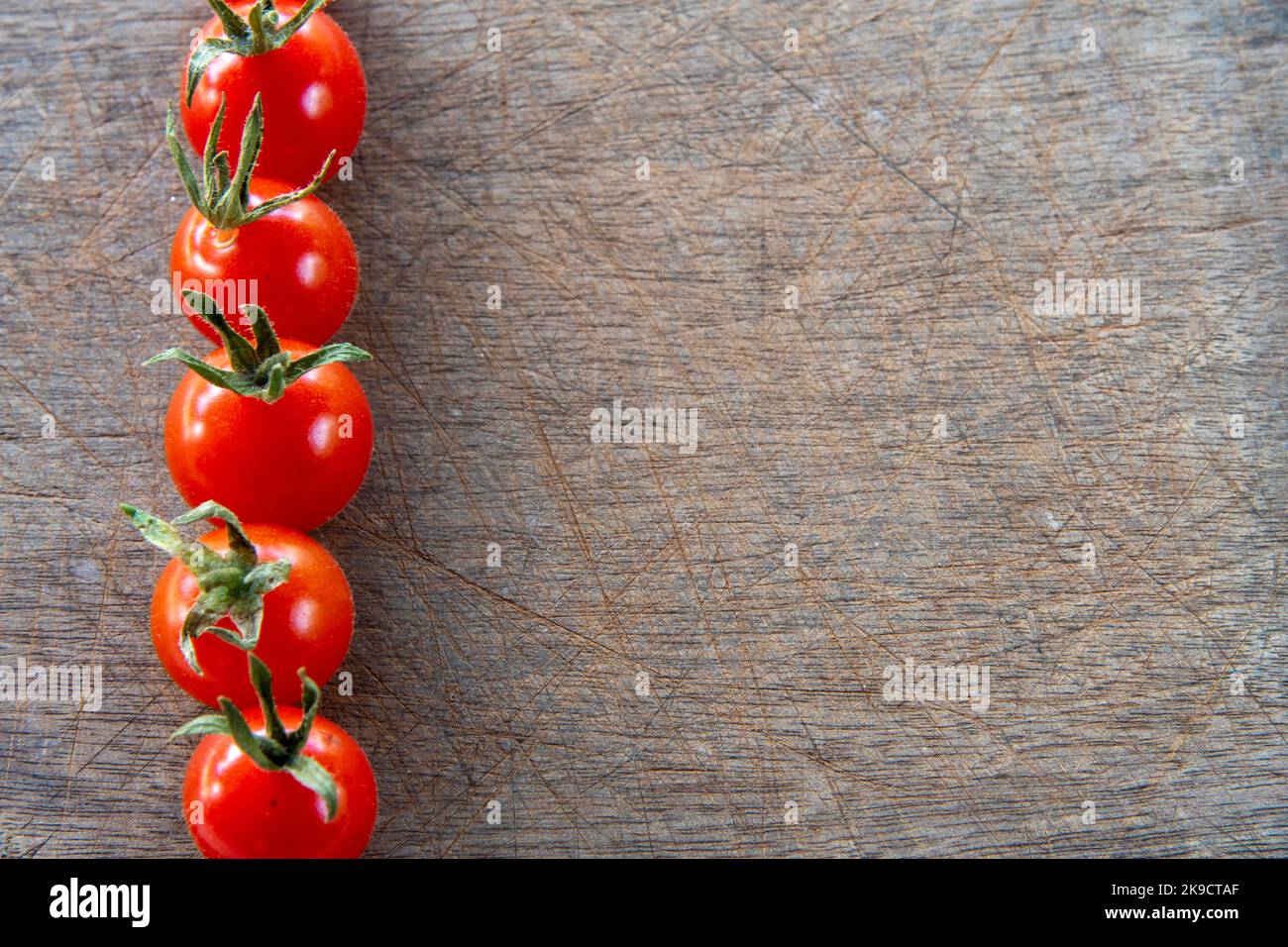 Cherry tomato forming side frame on scratched wooden background for ...