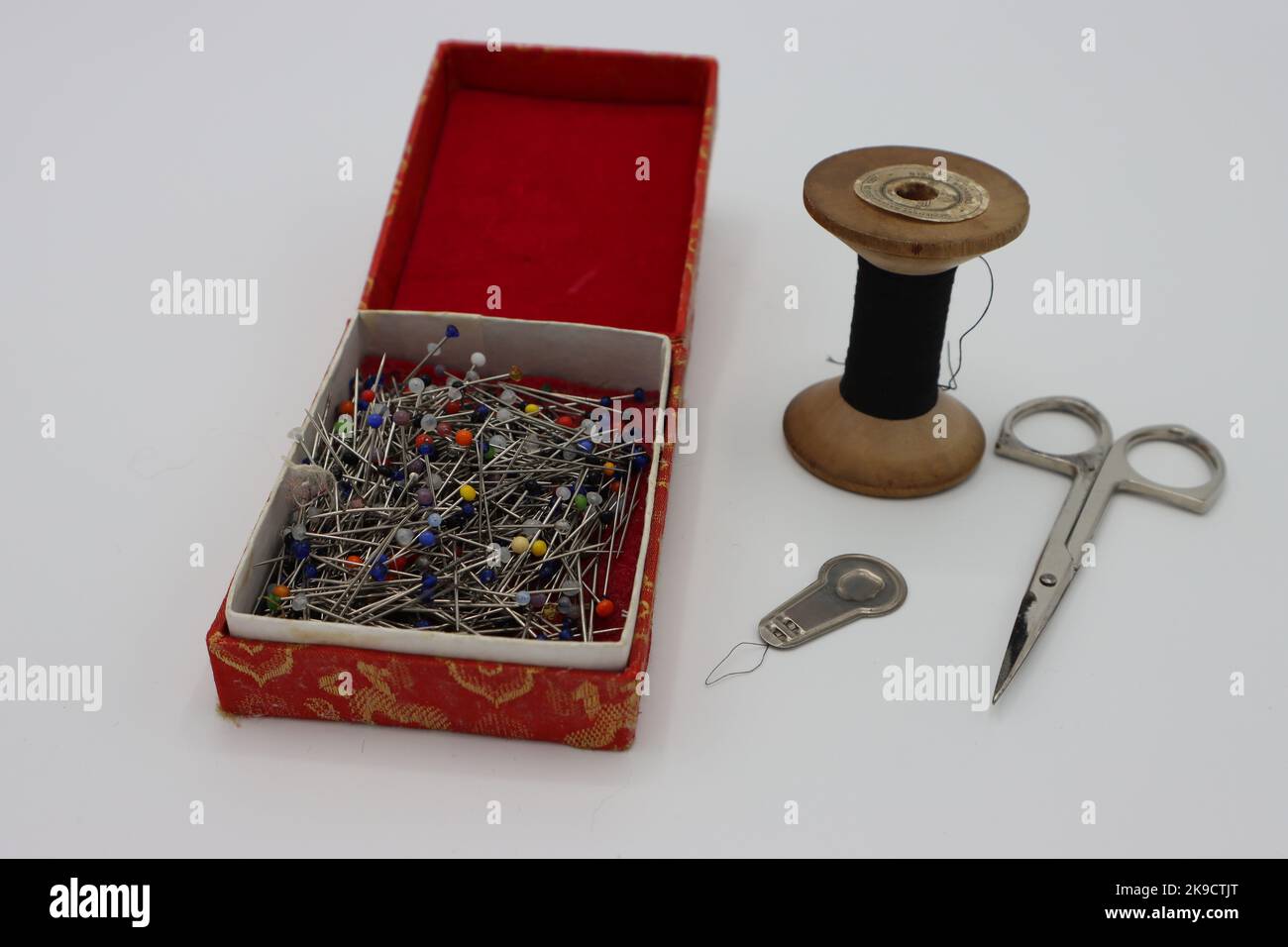 Sewing accessories on a white background. Pins in a box, thread on ...