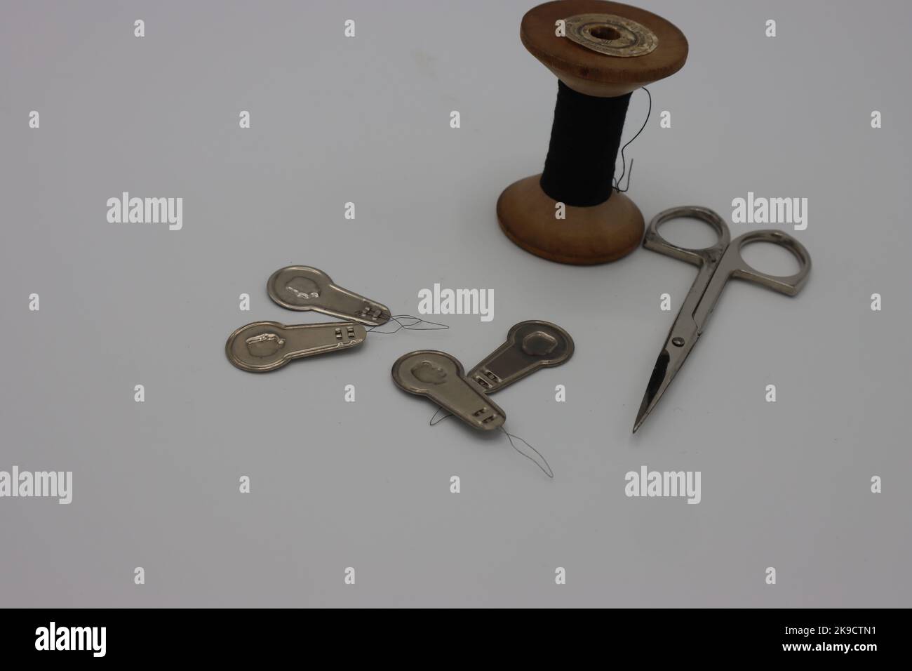 Sewing accessories on a white background. Needle threaders, thread and ...
