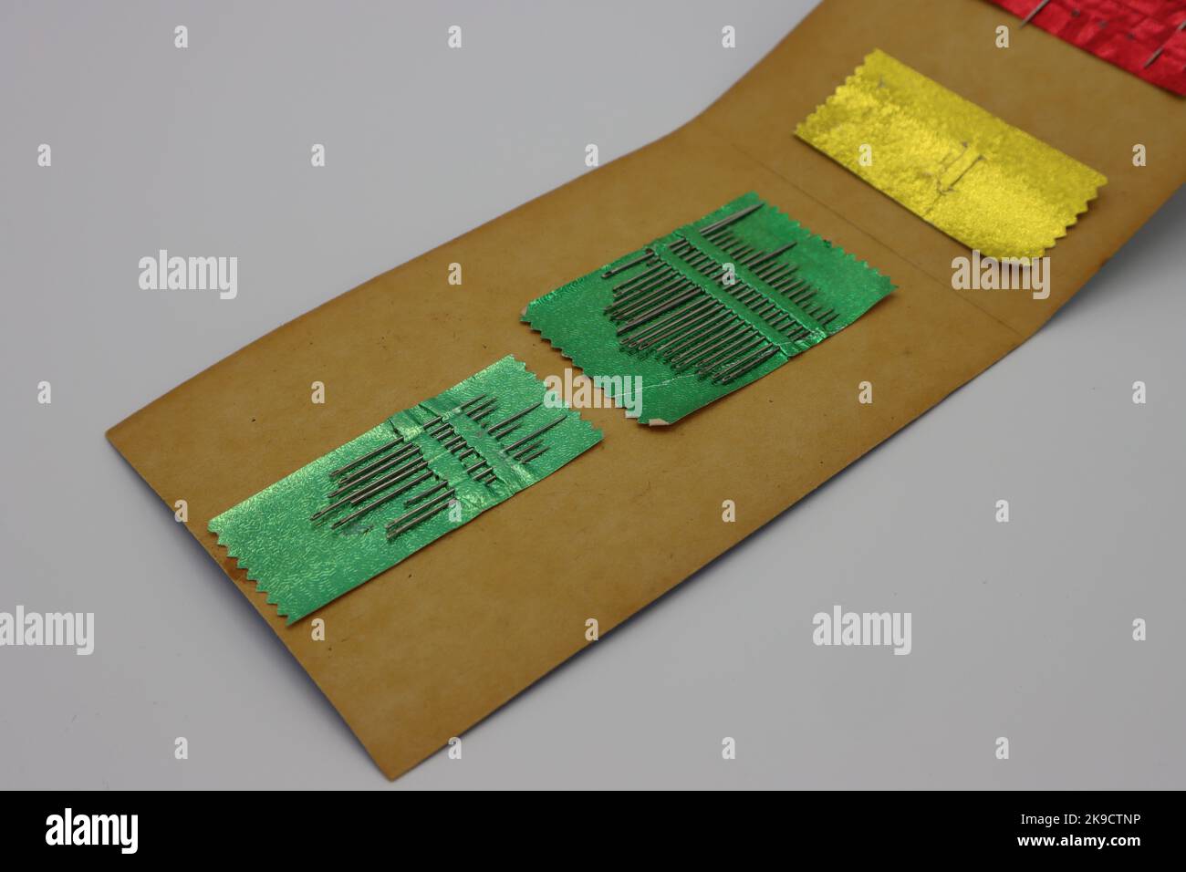 Sewing accessories on a white background. Sewing needles in paper ...