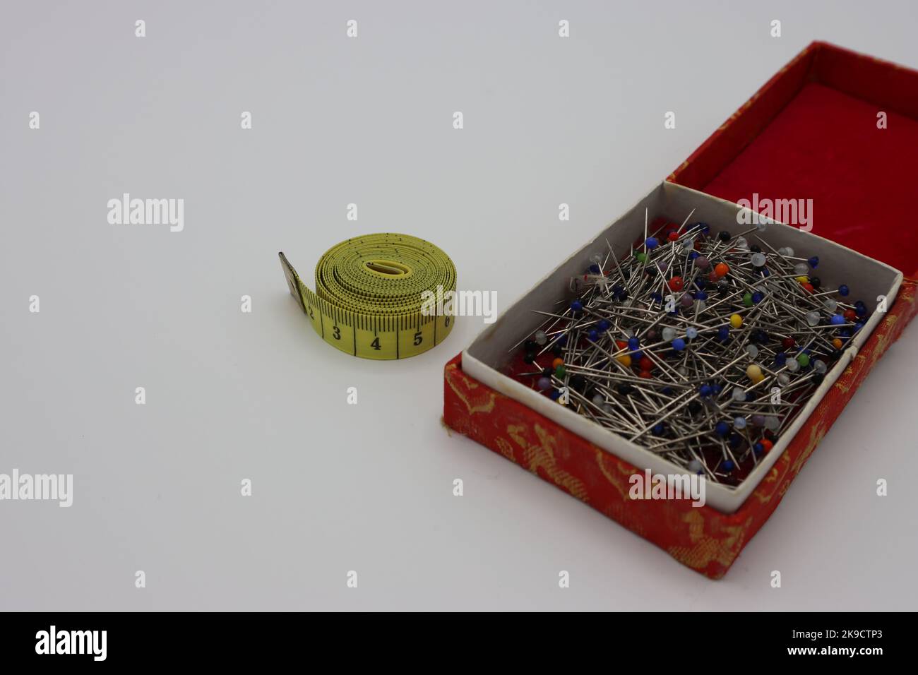 Sewing accessories on a white background. Measure tape and a red box ...
