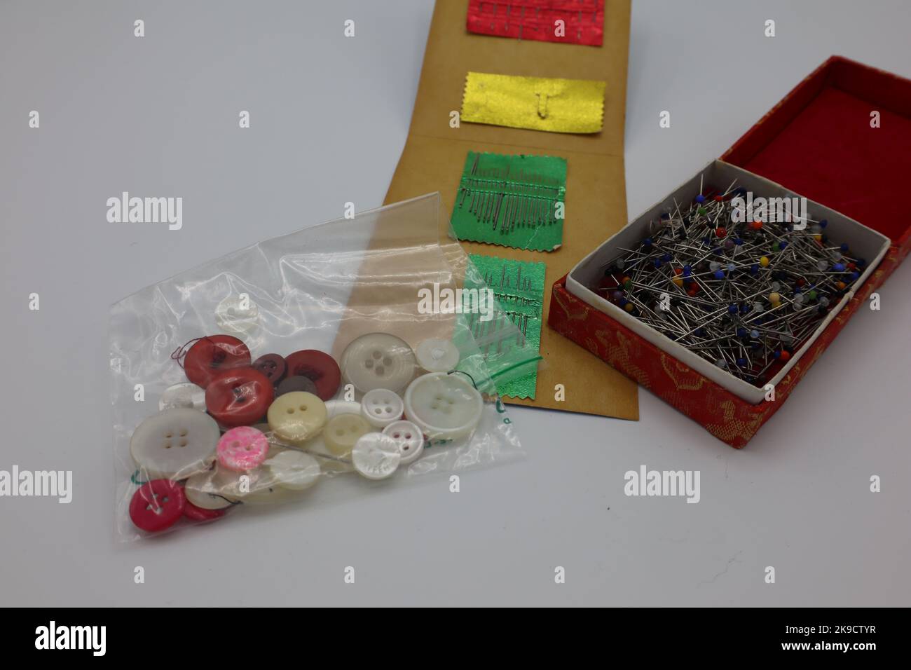Sewing accessories on a white background. Needles in a paper holder ...