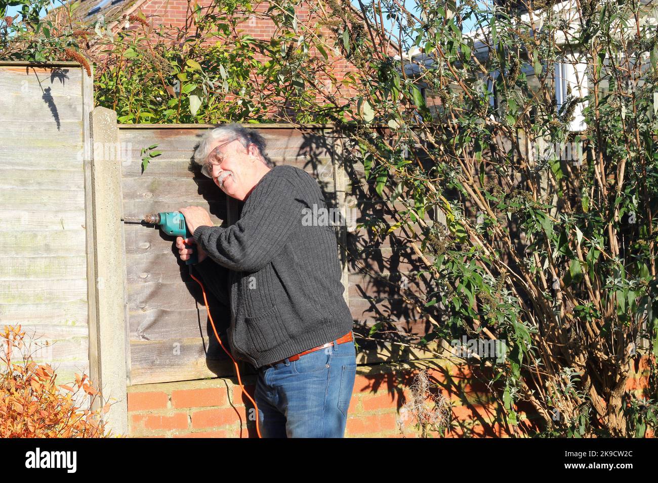Man using electric drill. Wearing eye protection. Mending a fence Stock ...