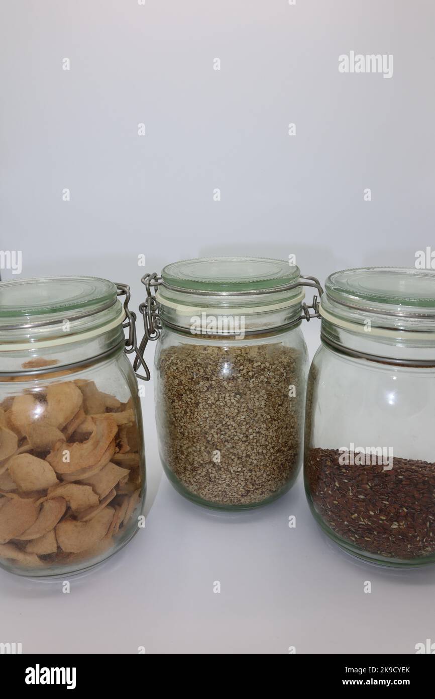 Glass jars filled with dried, dehydrated apple slices, sesame seeds and ...